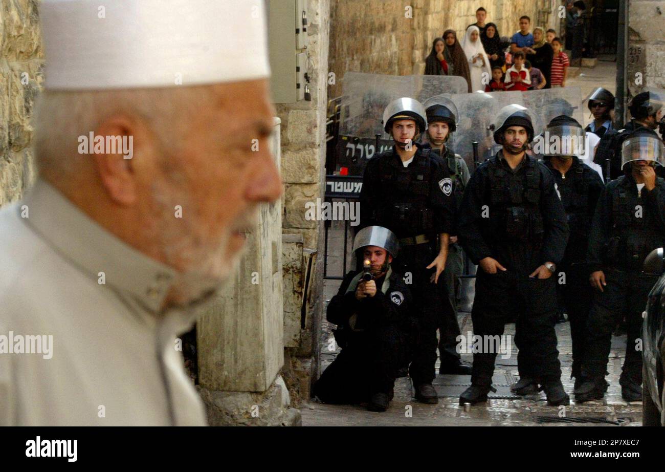 A Palestinian man, left, walks as Israeli police officers take ...