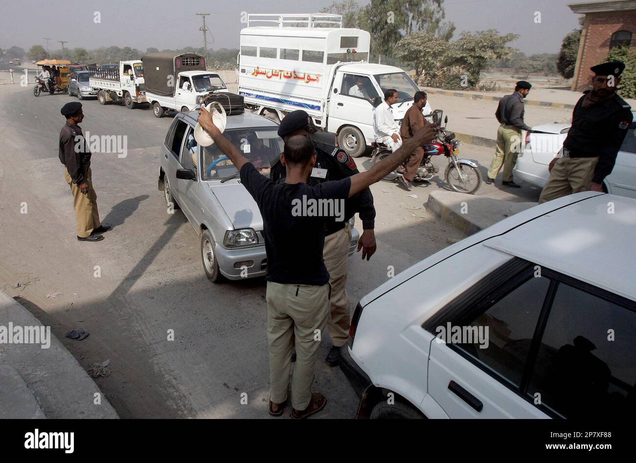 Pakistani police officers frisks a man at a checkpoint on the outskirts ...
