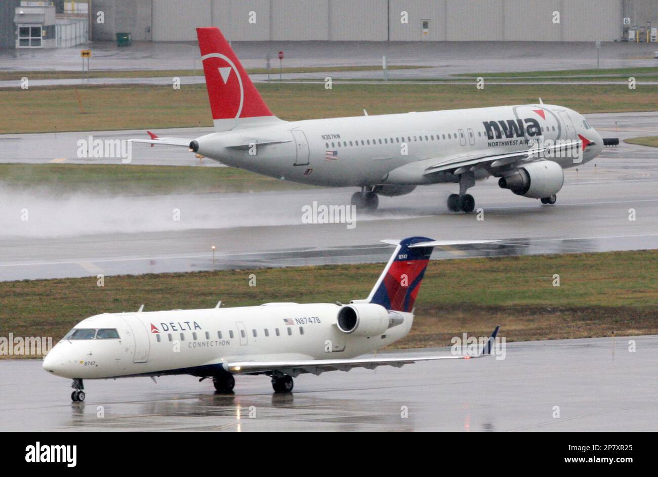 A Northwest Airlines jet kicks up water as it races down the runway for ...
