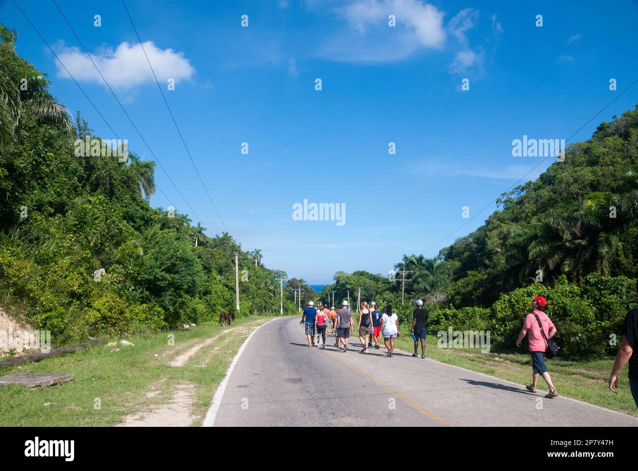 Tourists walk along a Cuban rural road to return to their resort after ...