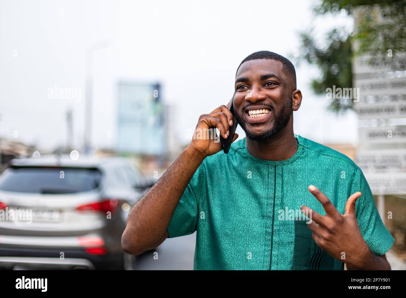 Excited young African man talking on smartphone outdoors, connects with ...