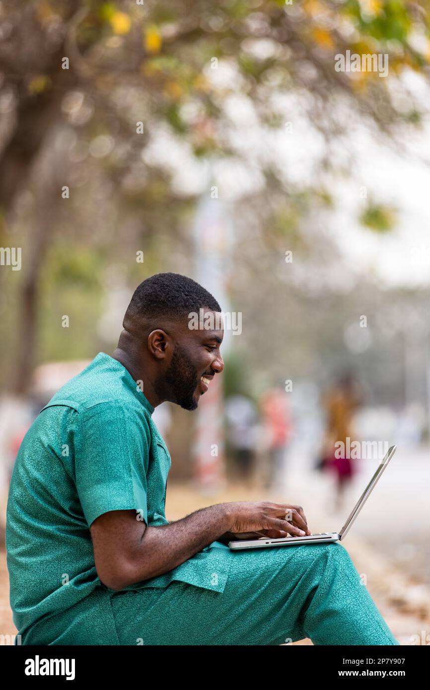 African Man with laptop computer outdoors, doing remote banking and ...