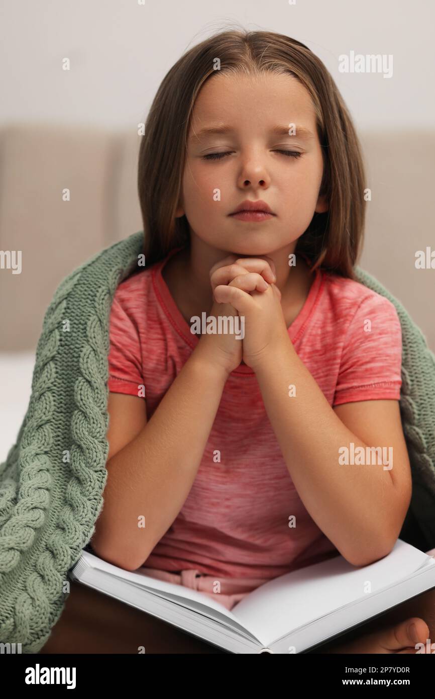 Cute little girl praying over Bible in bedroom Stock Photo - Alamy