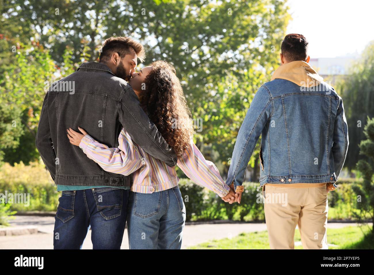 Woman kissing another man while holding hands with her boyfriend during ...