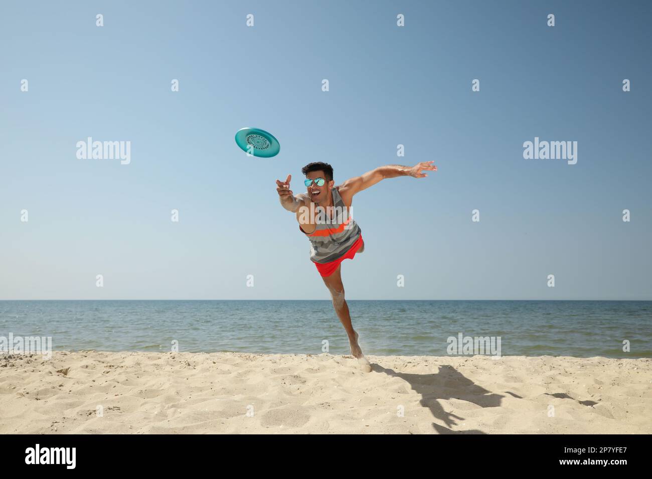 Sportive man jumping while trying to catch flying disk at beach Stock ...