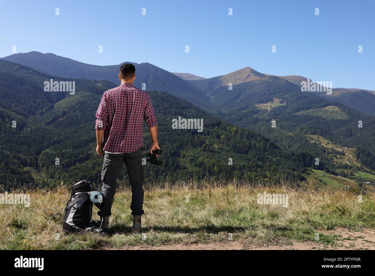 Tourist with hiking equipment and binoculars in mountains, back view ...