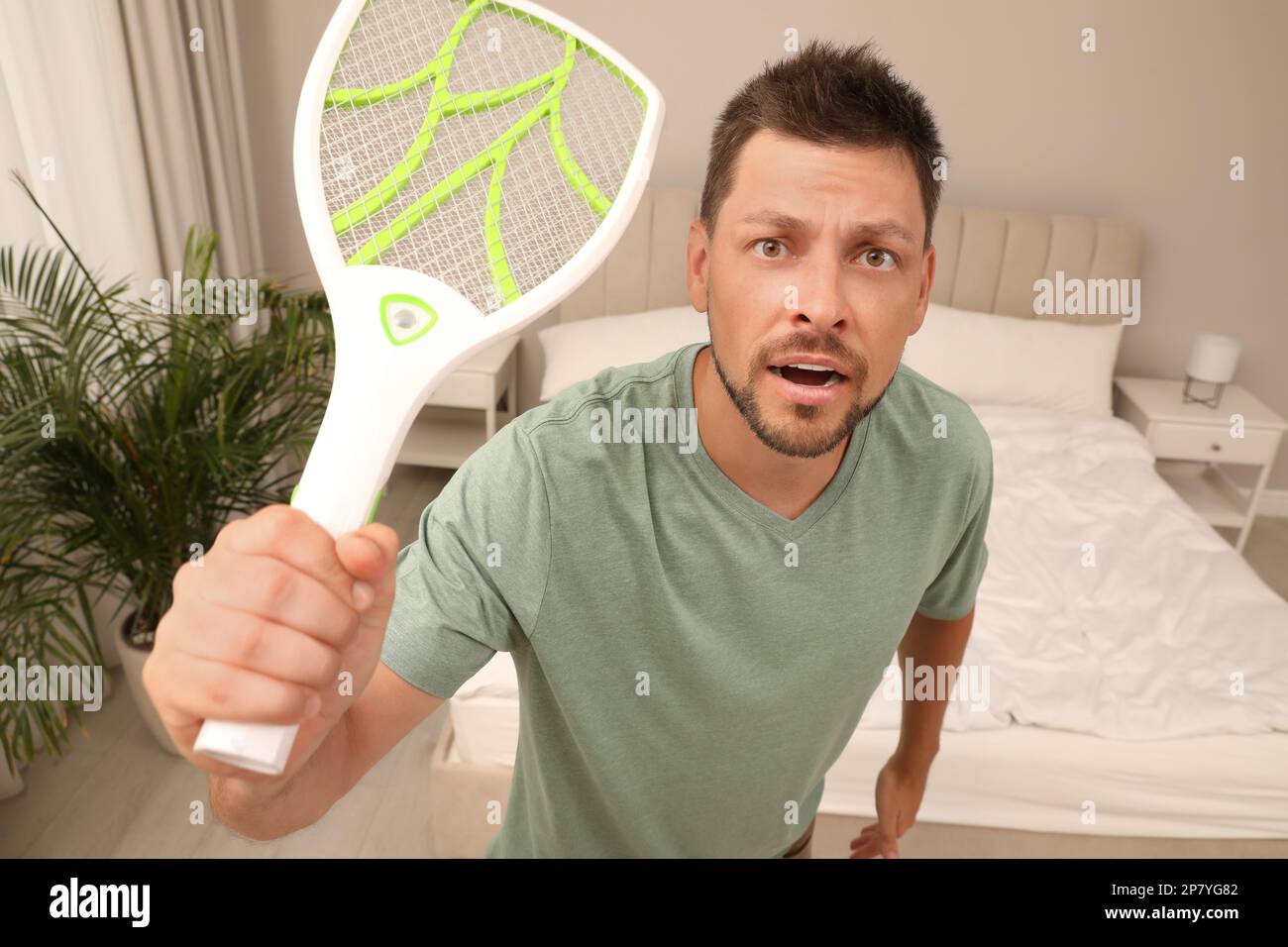 Man with electric fly swatter in bedroom. Insect killer Stock Photo - Alamy