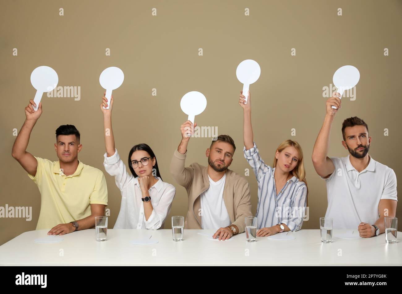 Panel of disappointed judges holding blank score signs at table on ...