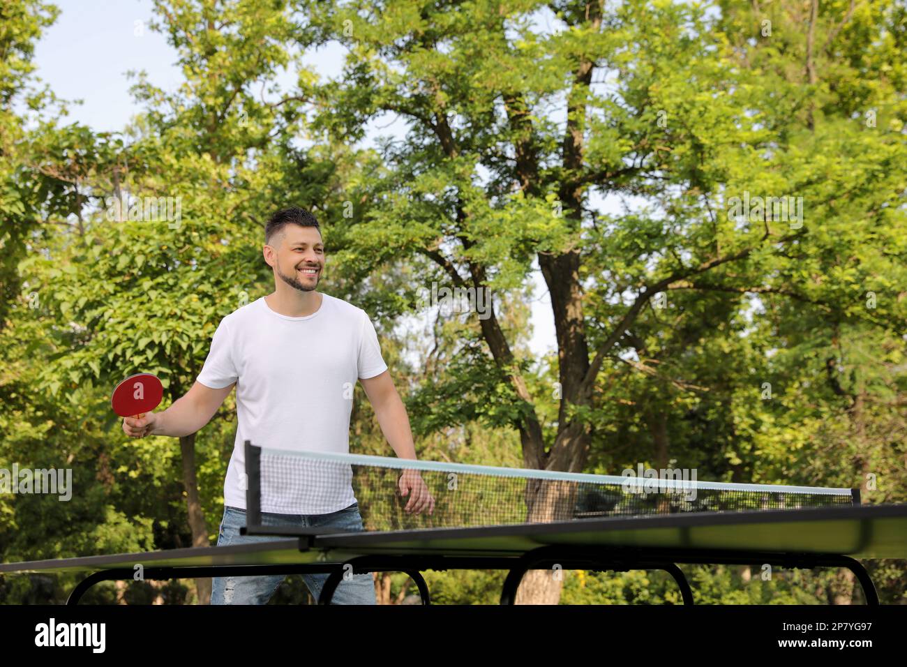 Happy man playing ping pong outdoors on summer day Stock Photo - Alamy