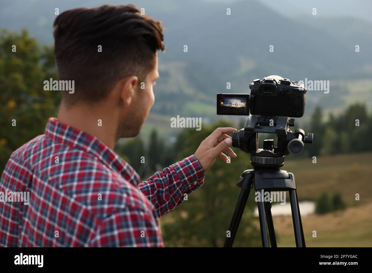 Man filming video with modern camera on tripod outdoors Stock Photo - Alamy