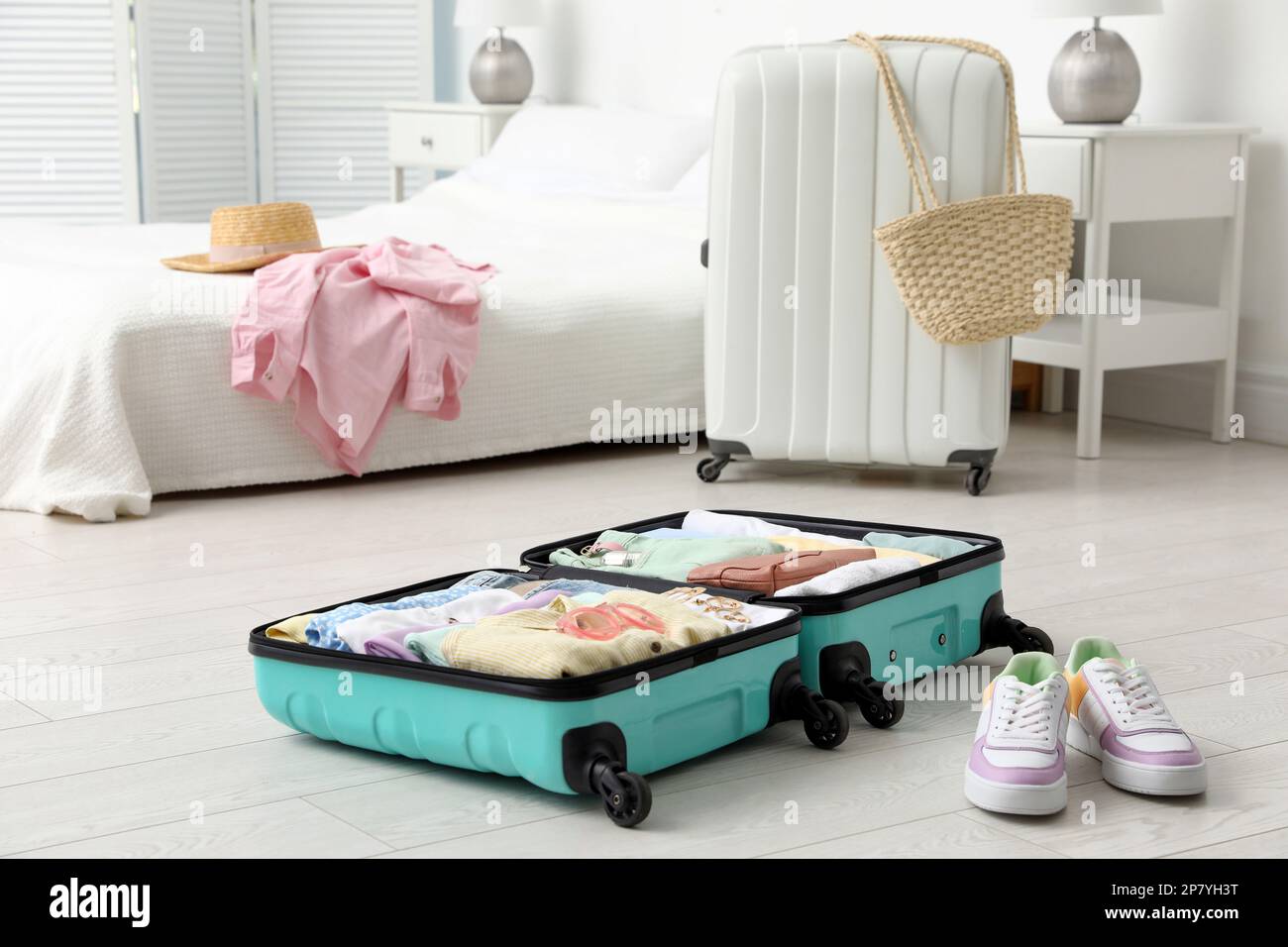 Open suitcase packed for trip and shoes on floor in room Stock Photo ...
