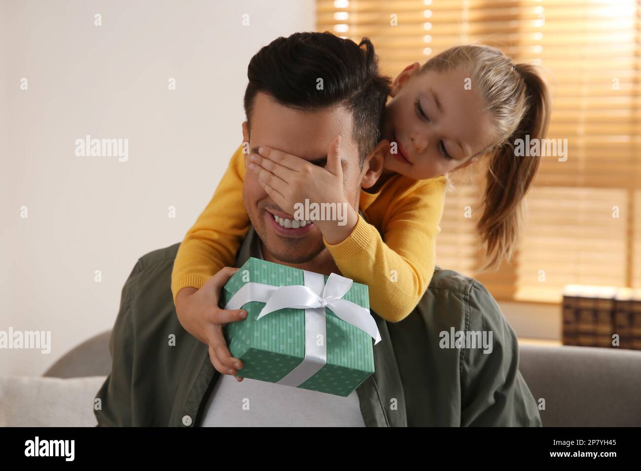 Man receiving gift for Father's Day from his daughter at home Stock ...