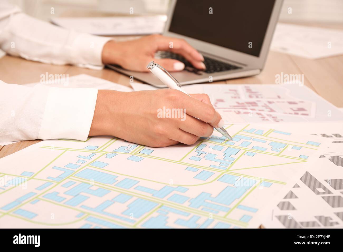 Professional cartographer working with cadastral map at wooden table ...