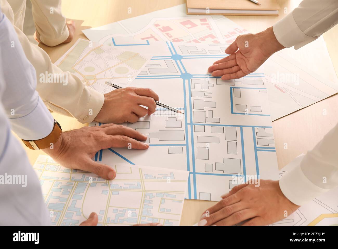 Professional cartographers working with cadastral map at table, closeup ...