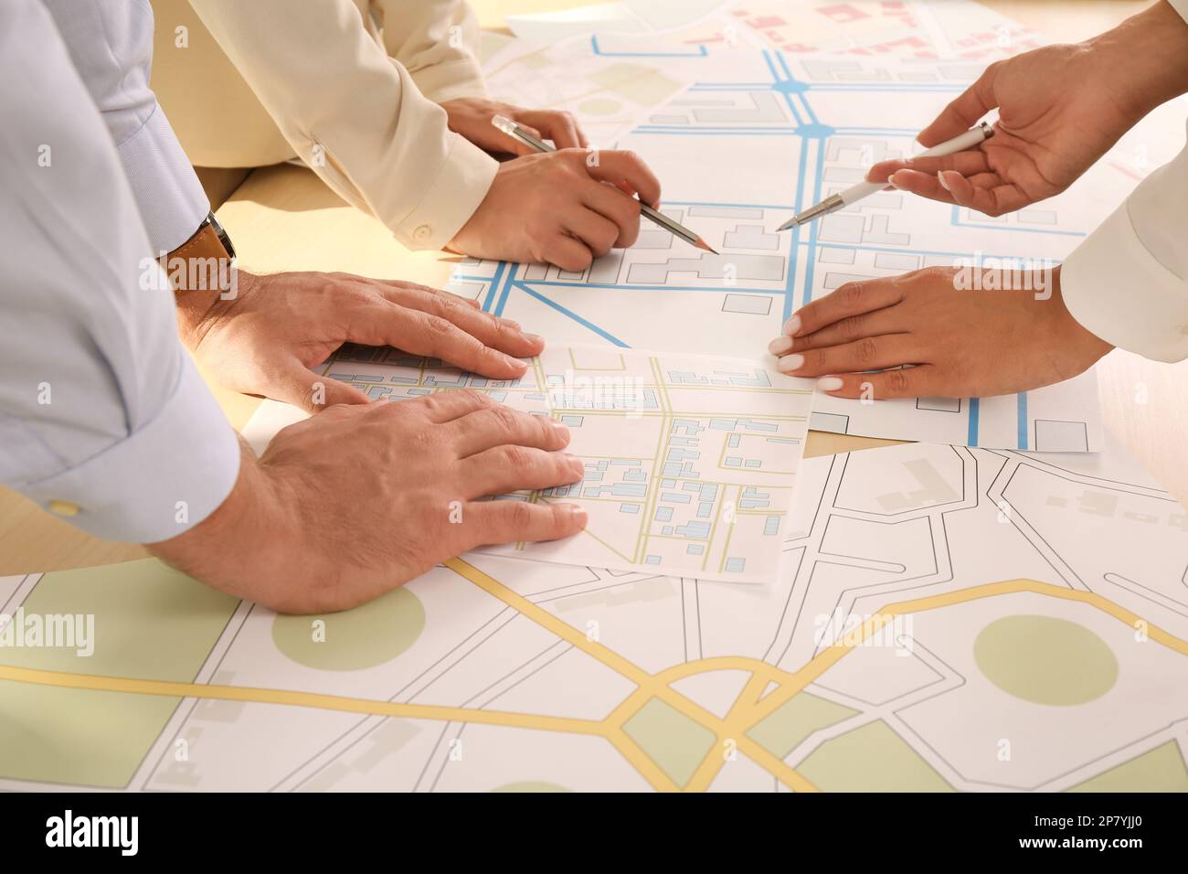 Professional cartographers working with cadastral map at table, closeup ...