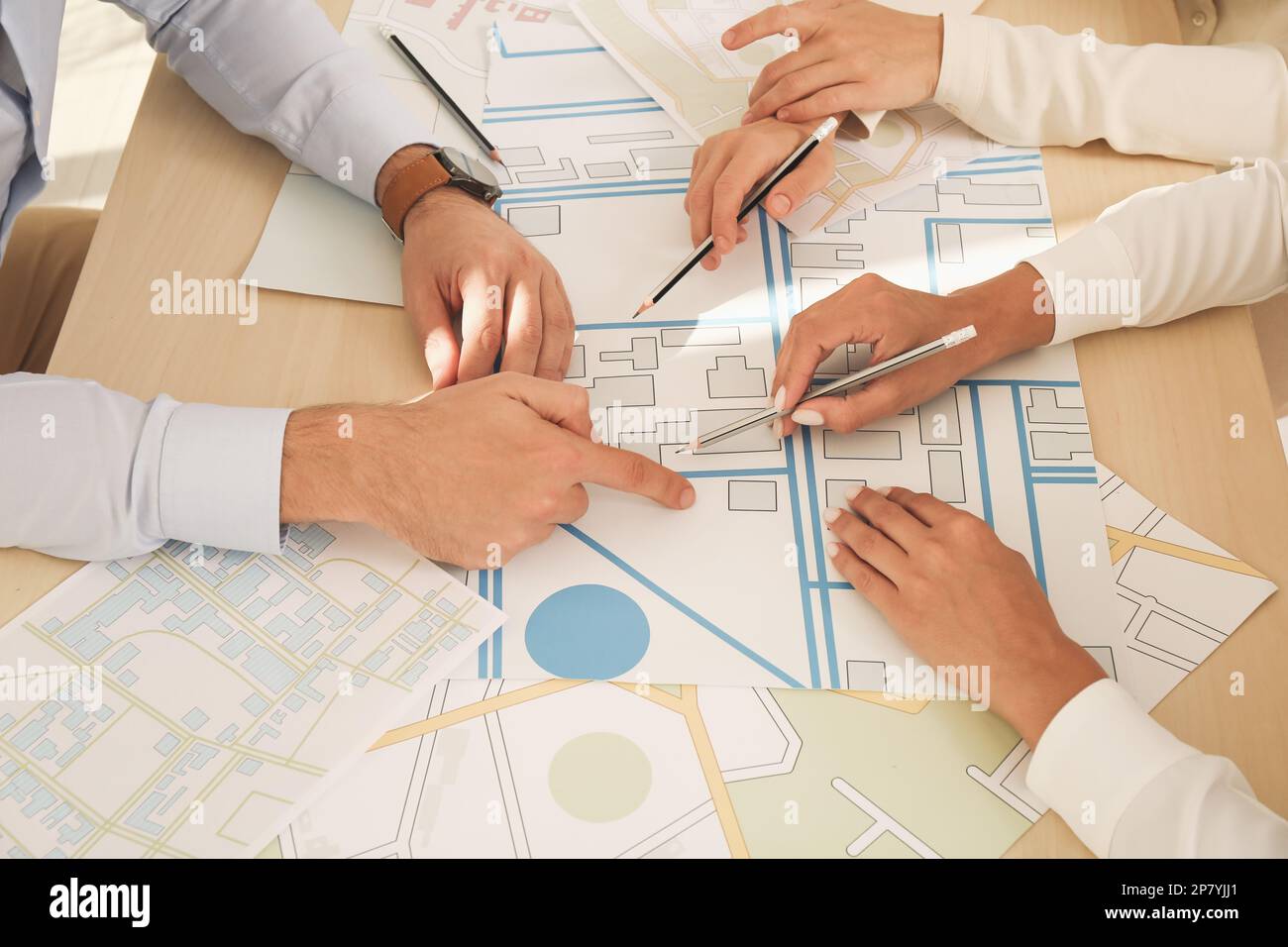 Professional cartographers working with cadastral map at table, closeup ...