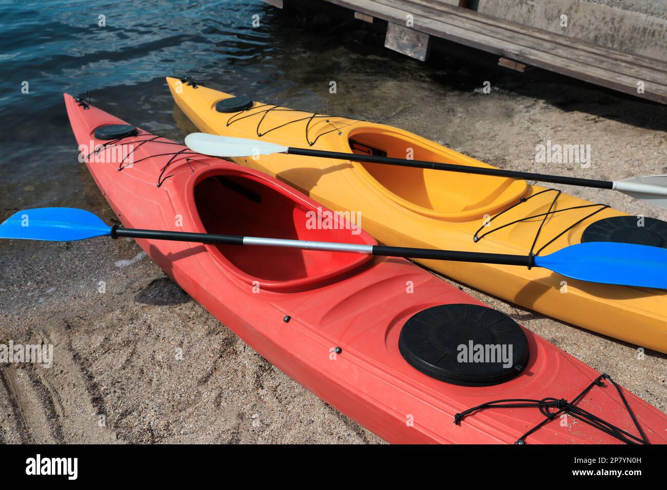 Modern kayaks with paddles on beach near river. Summer camp activity ...