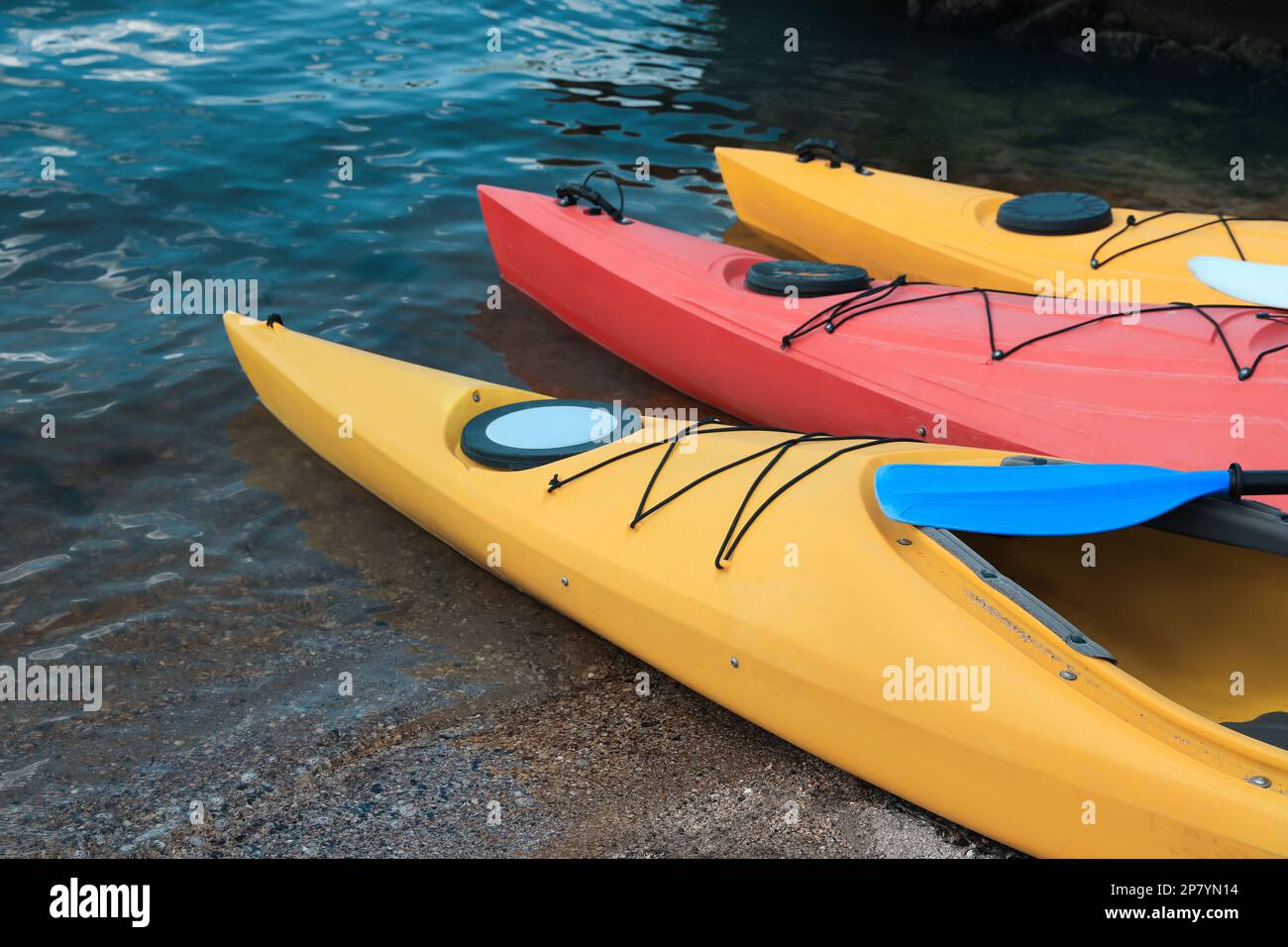 Modern kayaks with paddles on beach near river. Summer camp activity ...