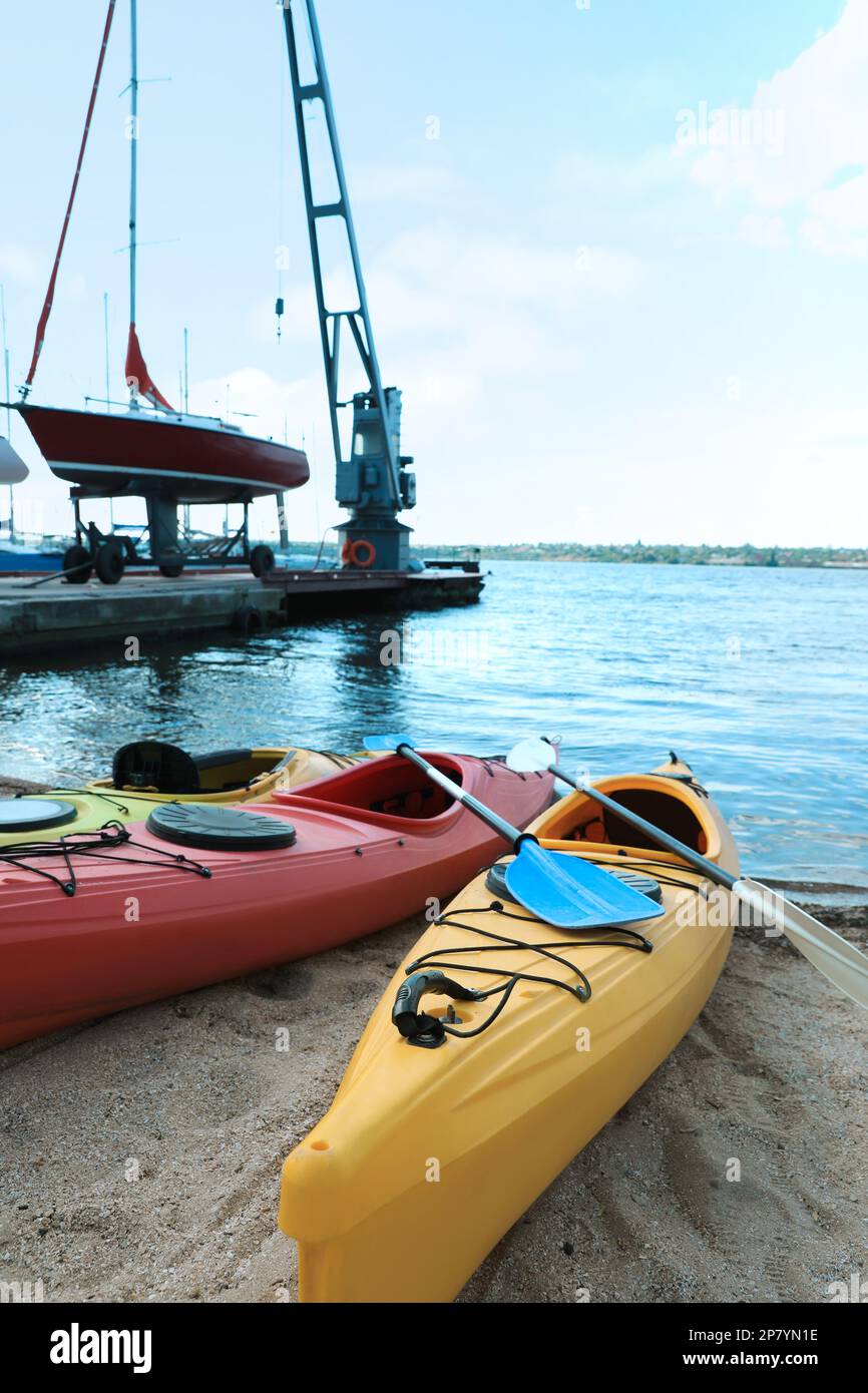 Modern kayaks with paddles on beach near river. Summer camp activity ...