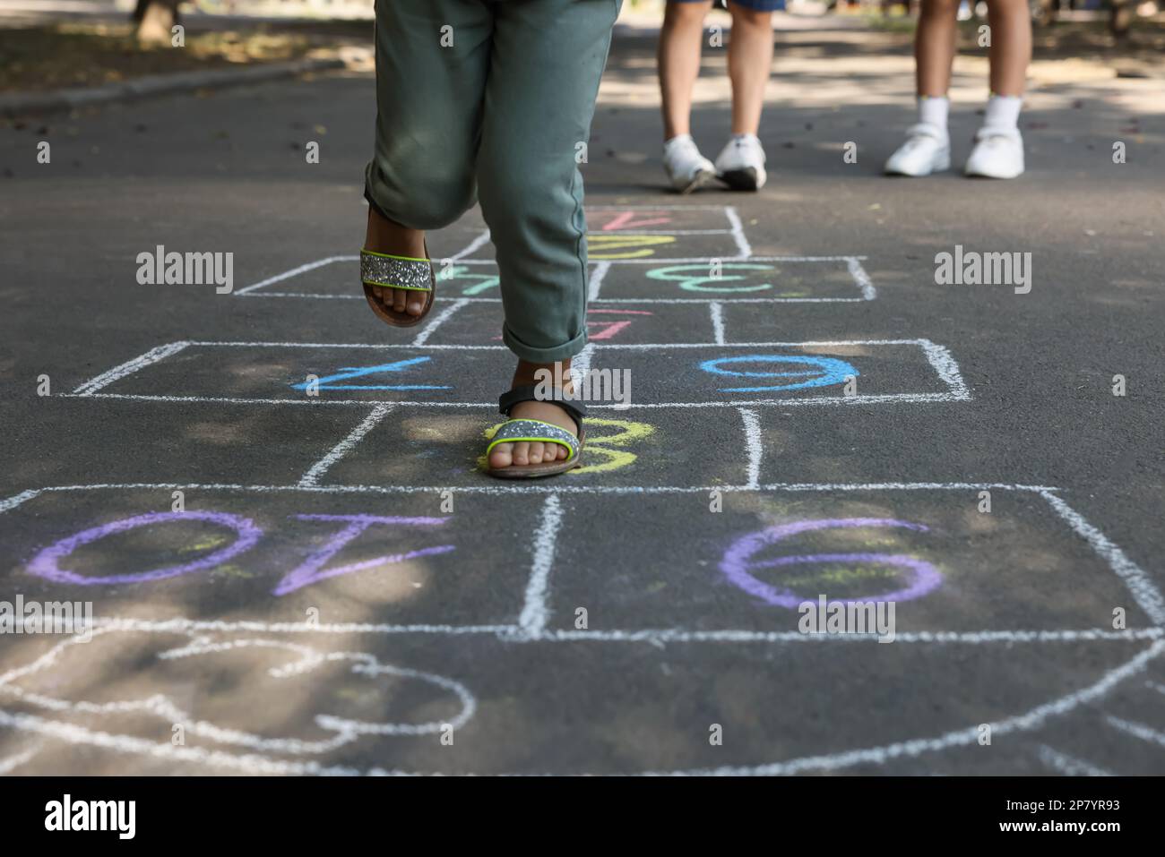 Little African American girl playing hopscotch drawn with chalk on ...