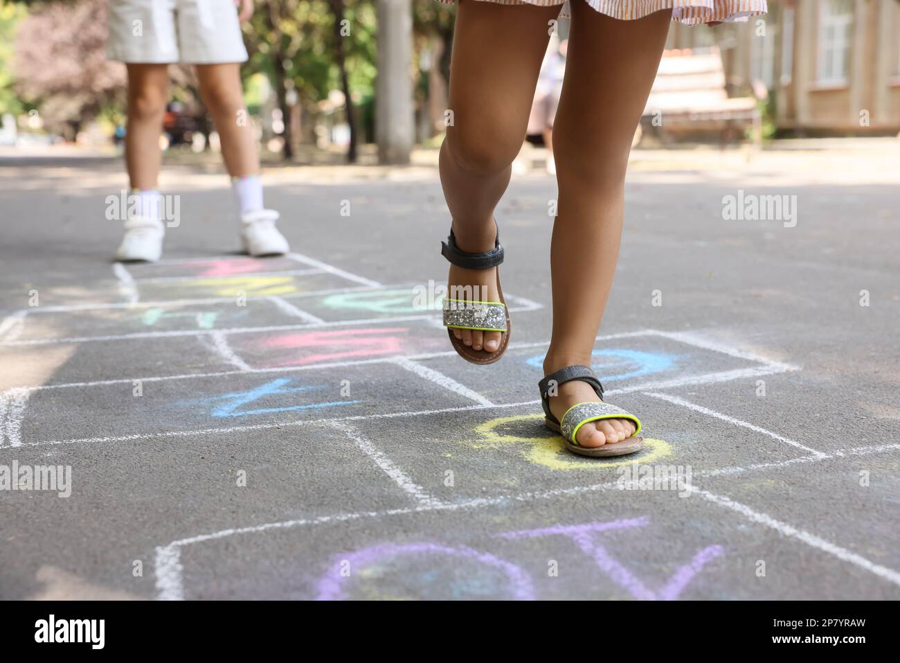 Little children playing hopscotch drawn with chalk on asphalt outdoors ...