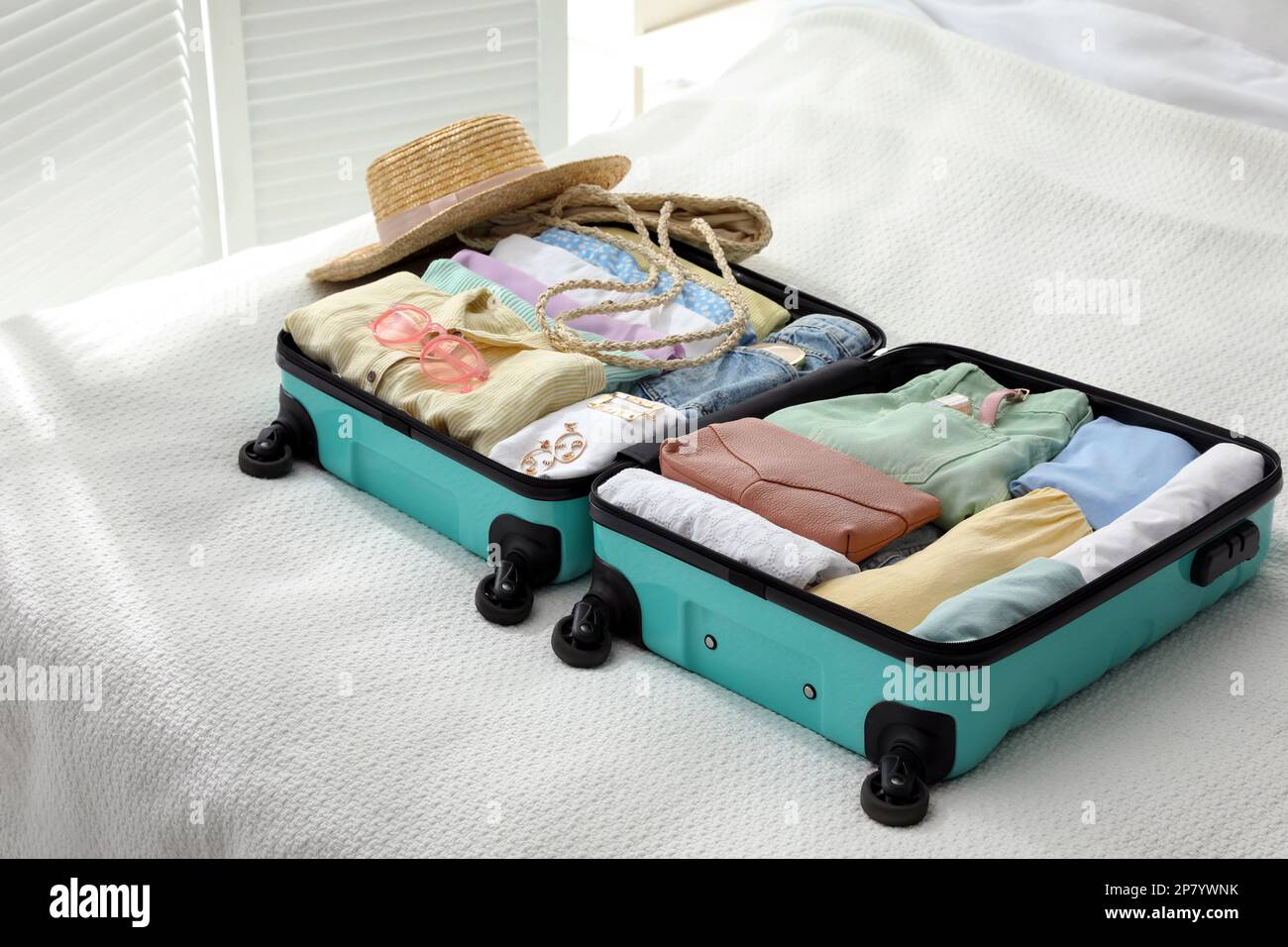 Open suitcase packed for trip and accessories on bed Stock Photo - Alamy