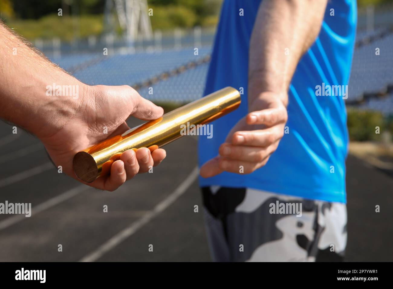 Man passing baton to his partner at stadium, closeup Stock Photo - Alamy
