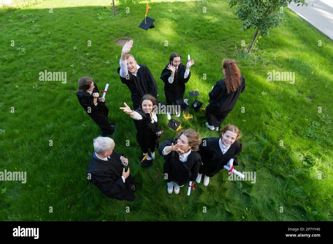 Classmates in graduation gowns throw their caps. View from above Stock ...