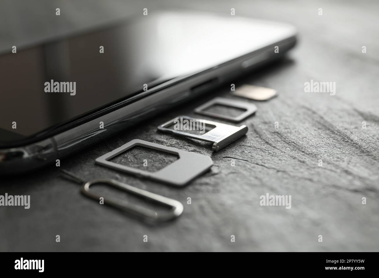 SIM card, mobile phone and ejector tool on grey table, closeup Stock ...