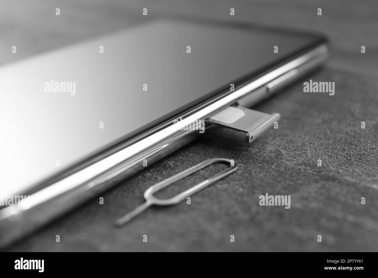 Mobile phone with Sim card in tray and ejector tool on grey table ...