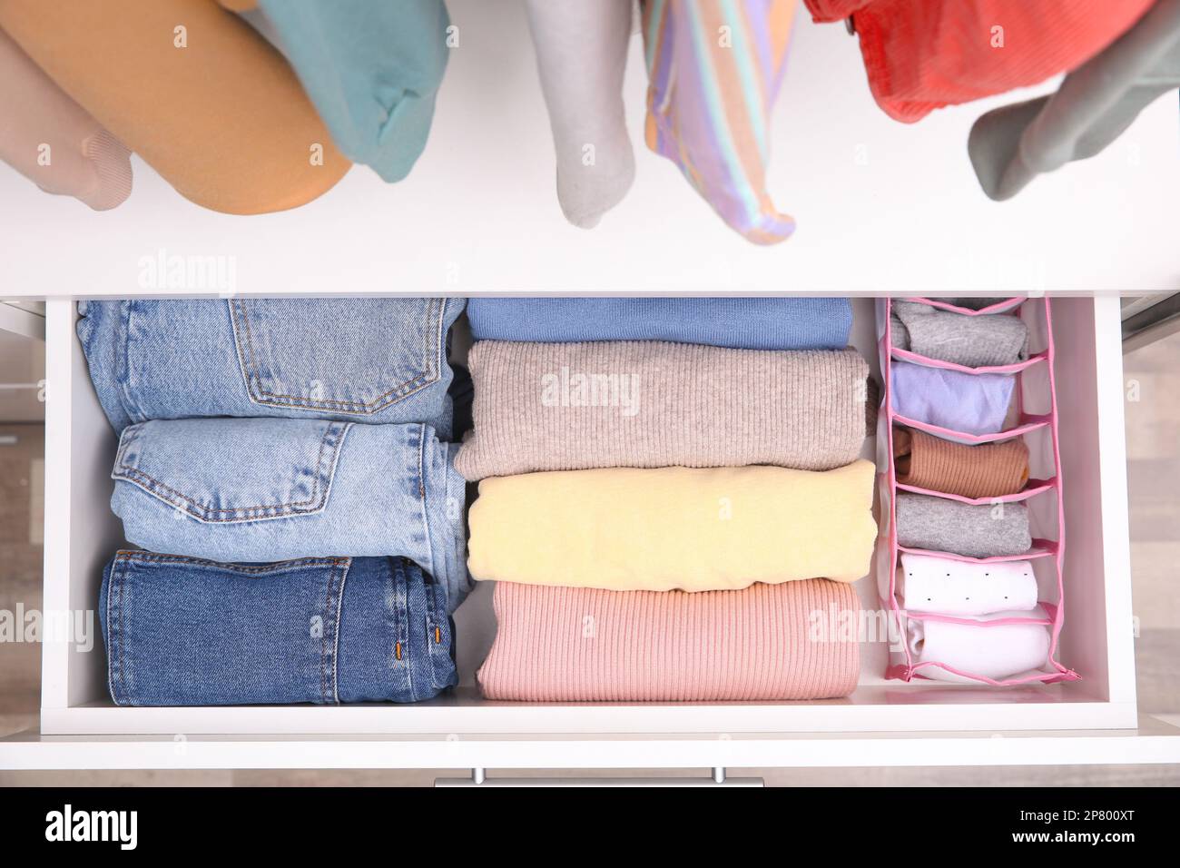 Open drawer with folded clothes indoors, top view. Vertical storage ...