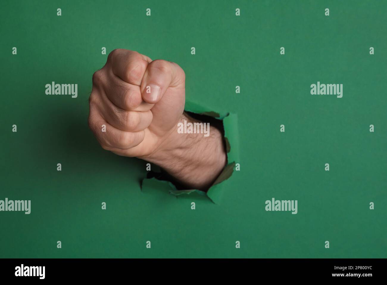 Man breaking through green paper with fist, closeup Stock Photo - Alamy