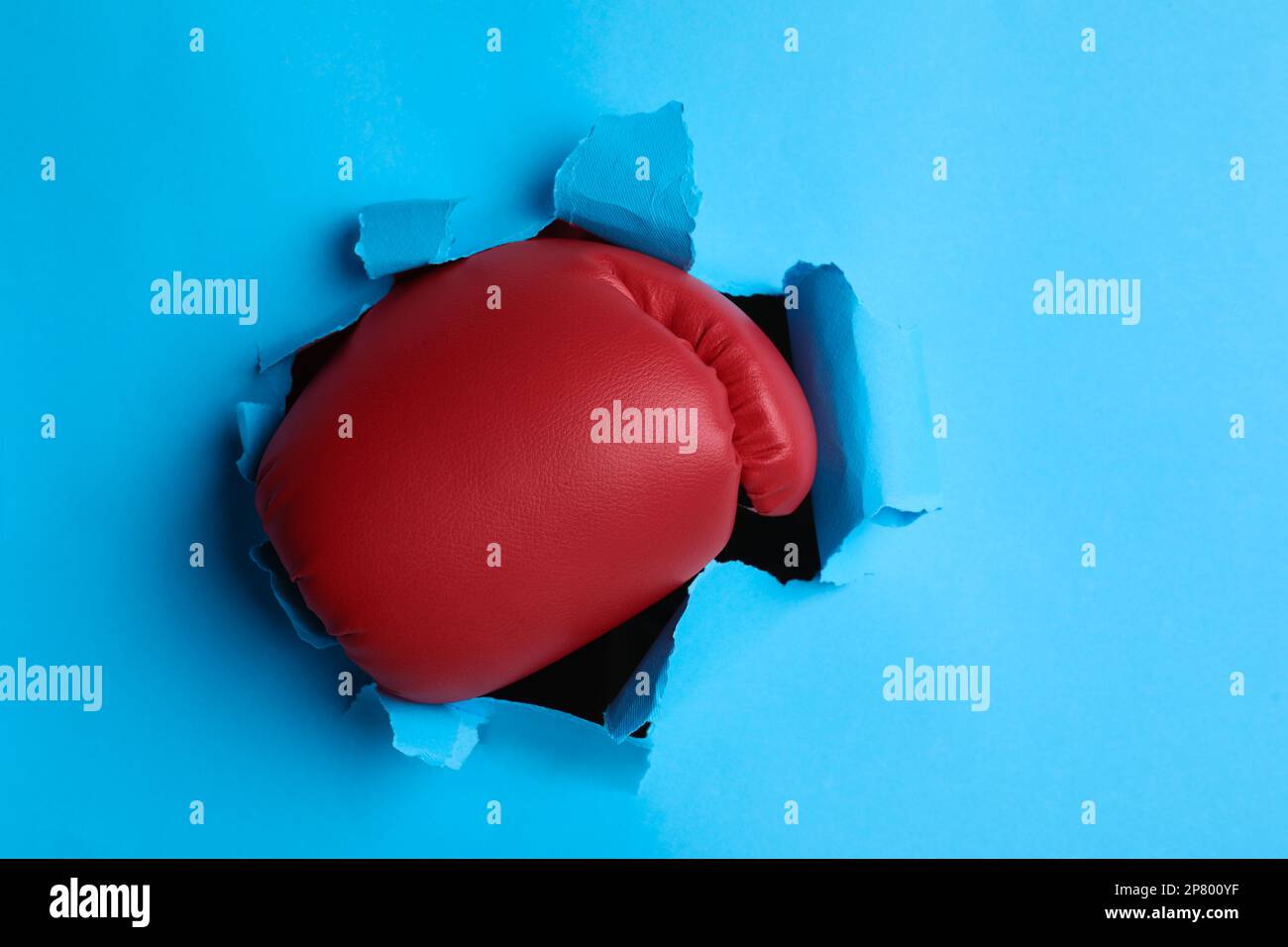 Man breaking through light blue paper with boxing glove, closeup Stock ...