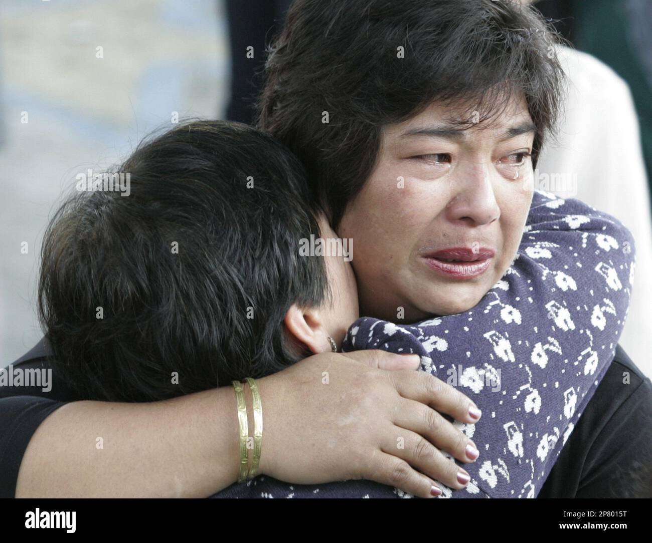 Filipino women hug each other as they grieve during the mass burial of ...