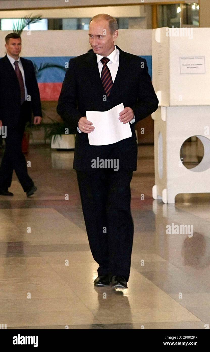 Russian Prime Minister Vladimir Putin carries his ballots at a polling ...