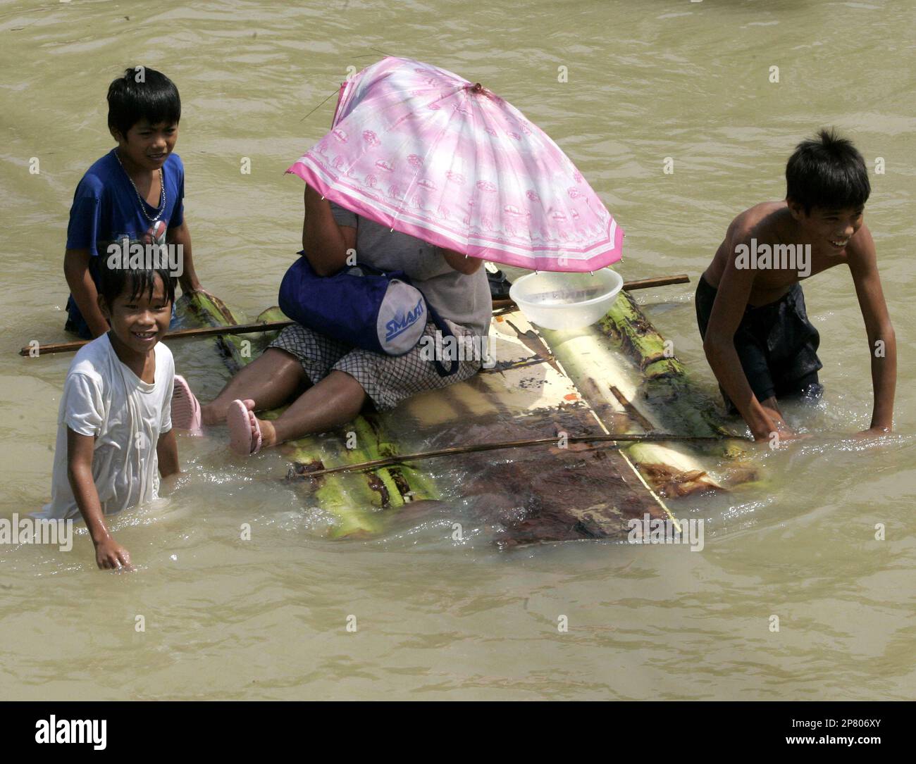 Boys transport a commuter using an improvised raft at Dagupan city ...