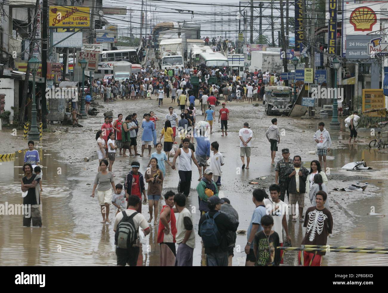People gather along a muddied highway following massive floodings at ...