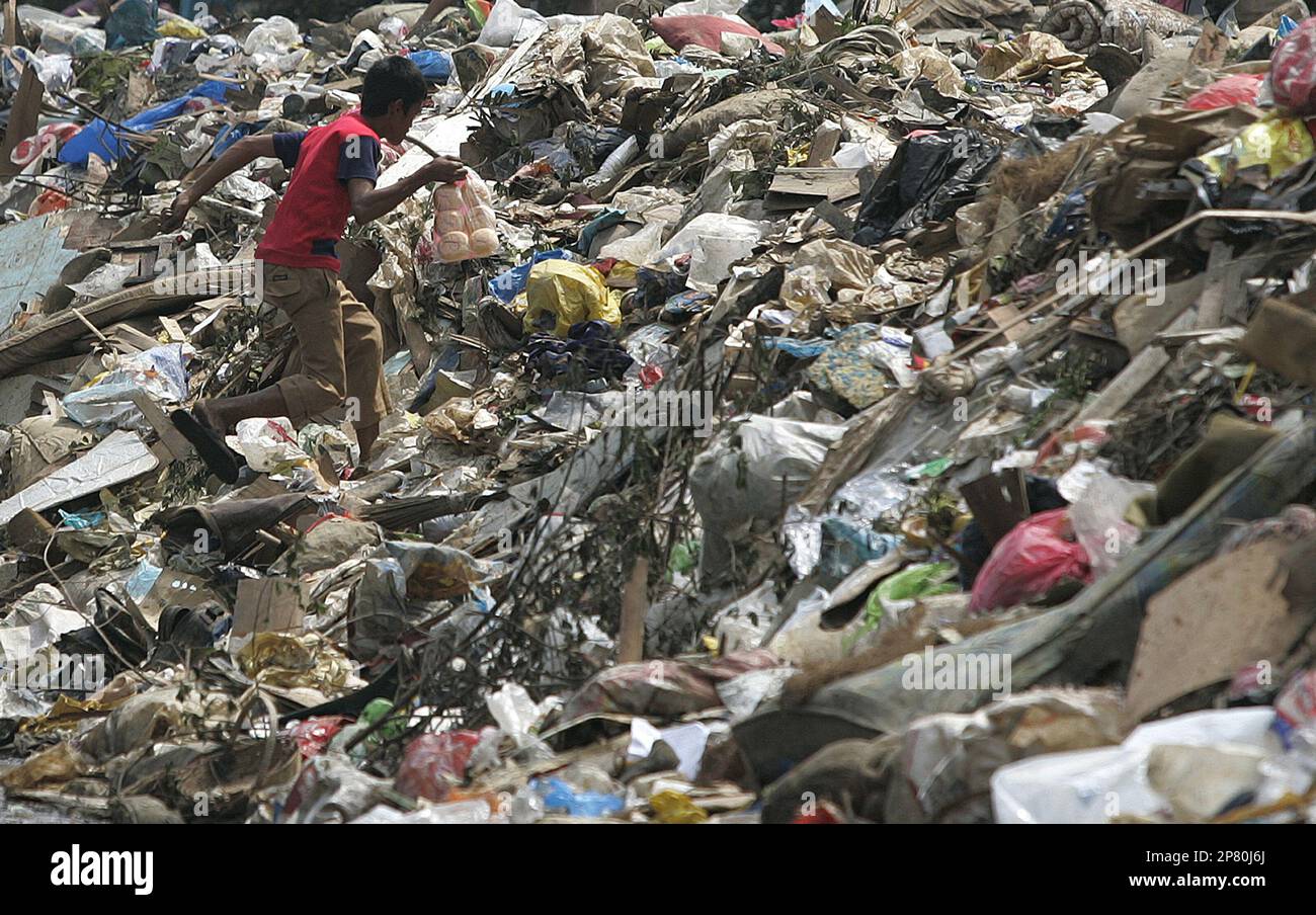 A Filipino boy carries bread buns as he runs up piles of garbage from ...