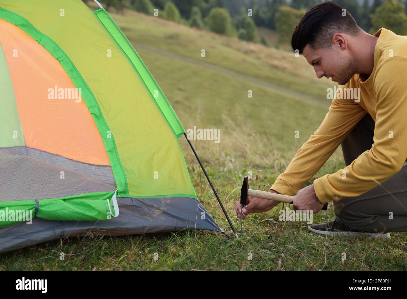 Man setting up camping tent on hill Stock Photo - Alamy