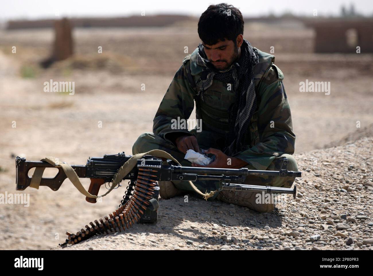 An Afghan Army soldier sits with his machine gun following a firefight ...