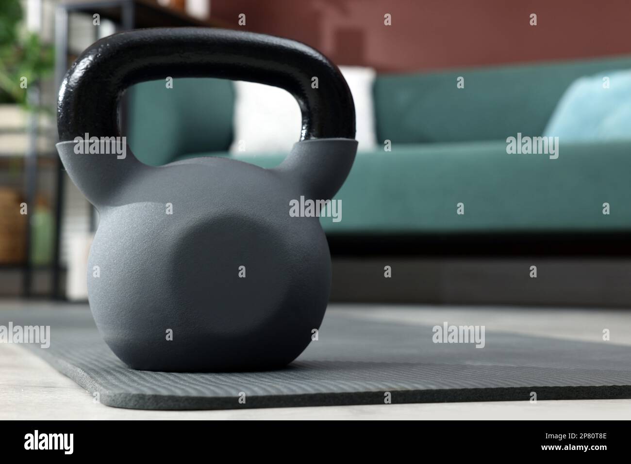 Kettlebell and grey yoga mat on floor in room. Space for text Stock ...