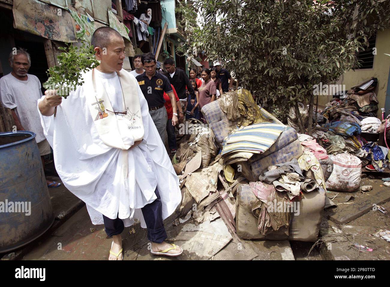 Catholic priest Father Robert Reyes uses a tree branch as he sprinkles ...