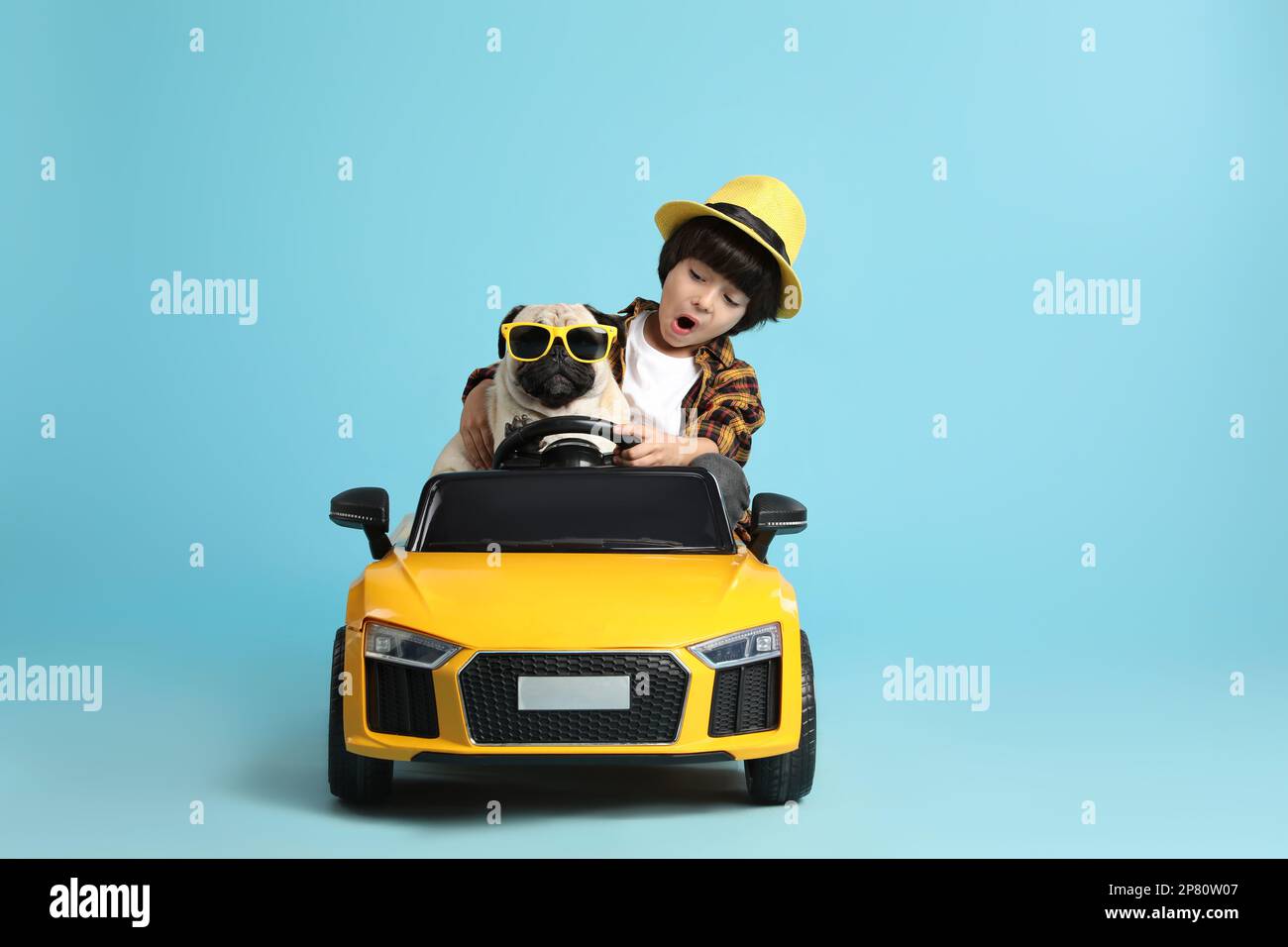 Little boy with his dog in toy car on light blue background Stock Photo ...
