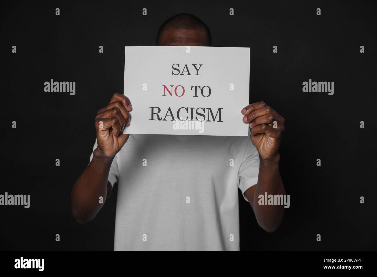 African American man holding sign with phrase Say No To Racism on black ...