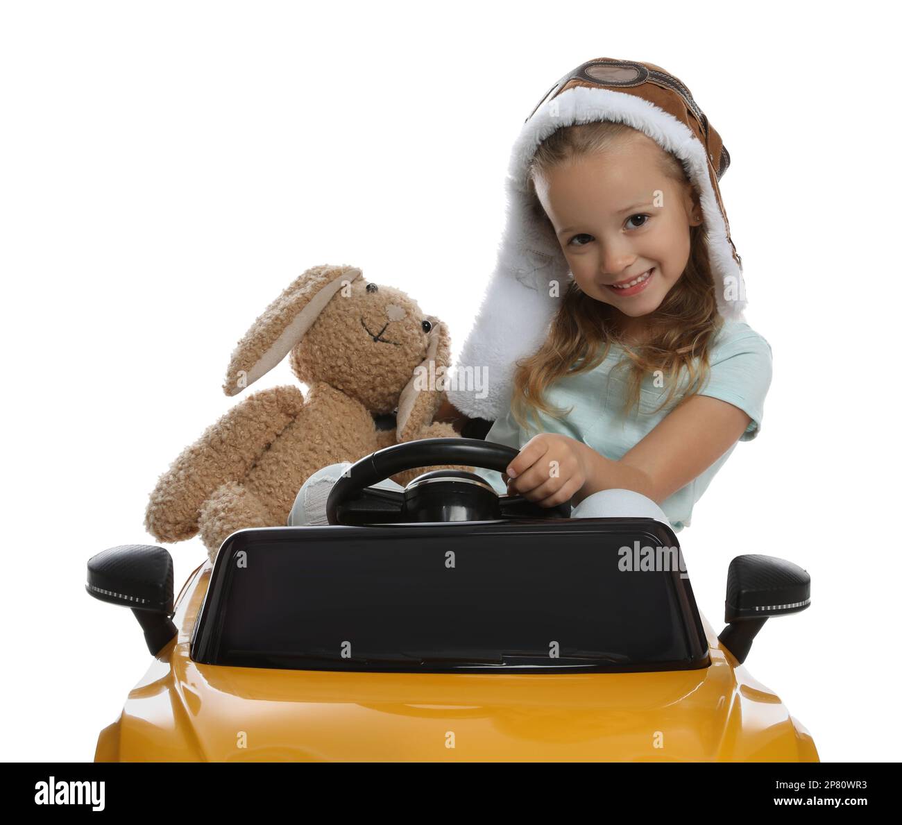 Cute little girl with toy bunny driving children's car on white ...