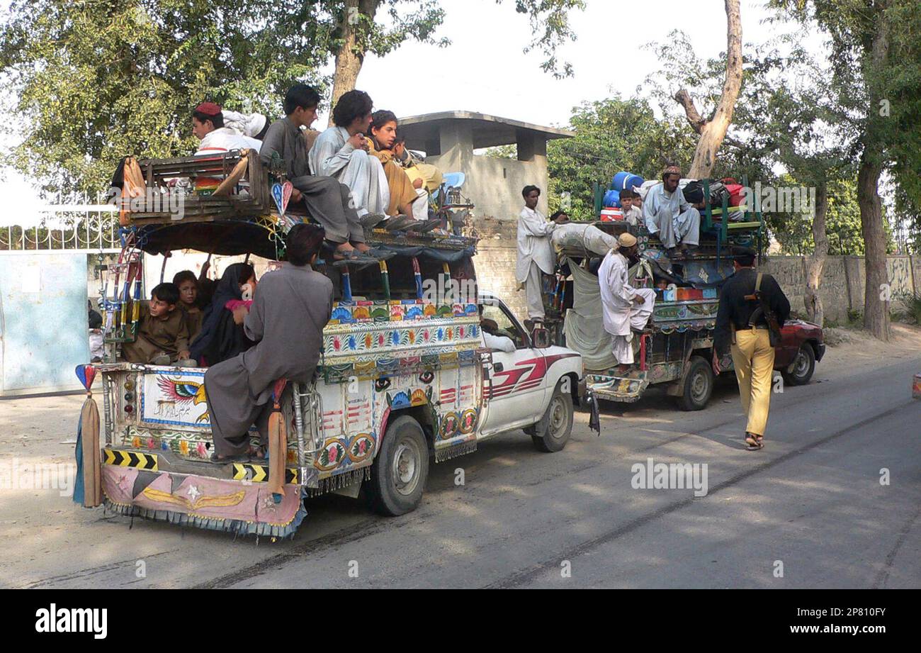 A Pakistani police officer walks toward a vehicle, carrying tribal ...