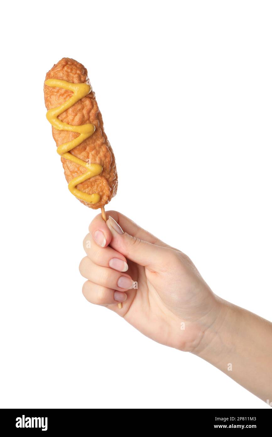 Woman holding delicious deep fried corn dog with mustard on white ...