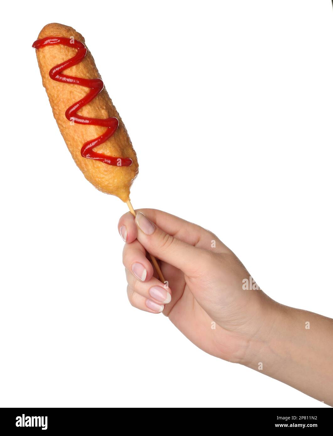 Woman holding delicious deep fried corn dog with ketchup on white ...