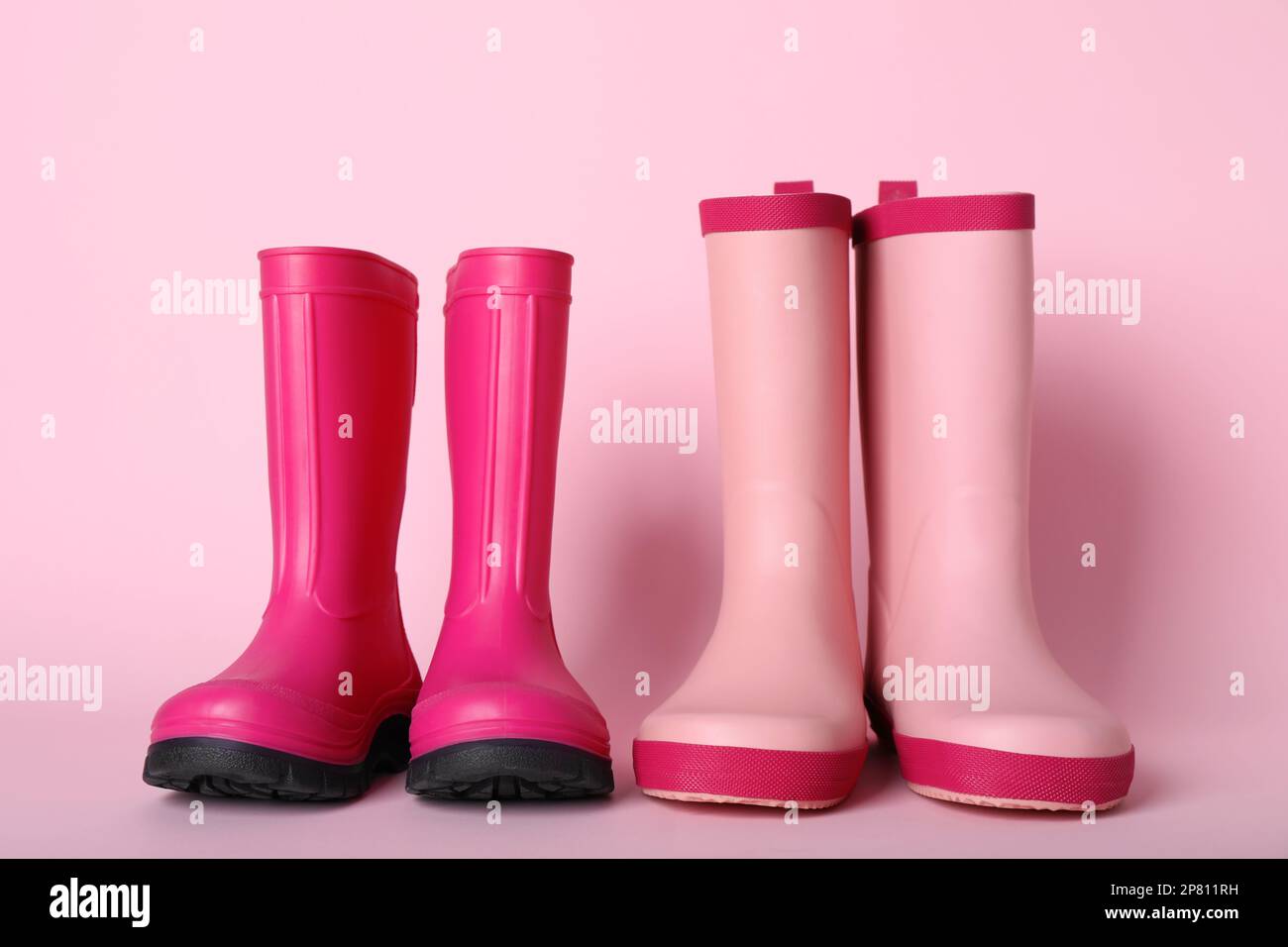 Two pairs of rubber boots on pink background Stock Photo - Alamy