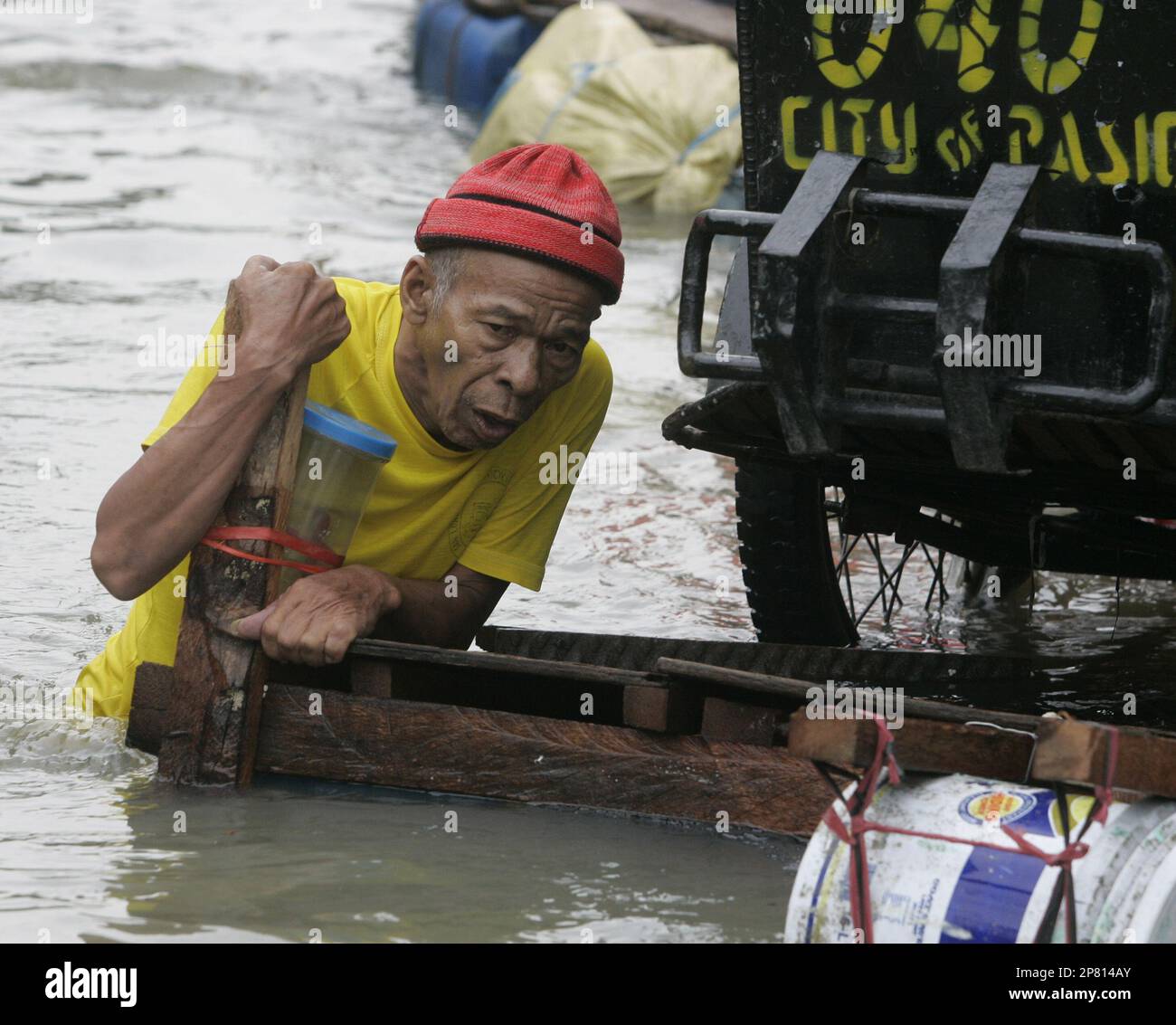 A man clings onto an improvised raft as he goes on his daily business ...